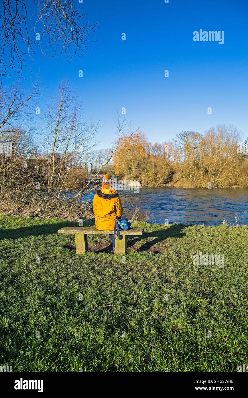 A woman wearing a bright yellow jacket and hat sits gazing at Buscot ...