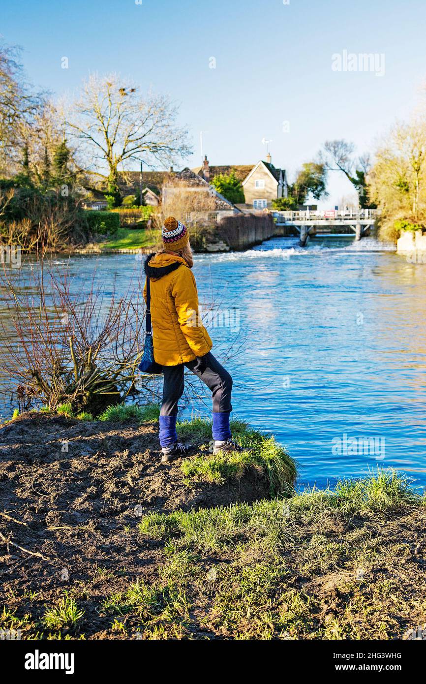 A woman wearing a bright yellow jacket and hat stands gazing at Buscot ...