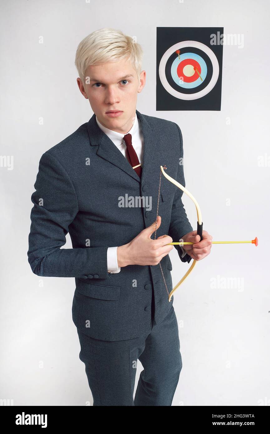 Young man holding bow and archery target in background Stock Photo - Alamy