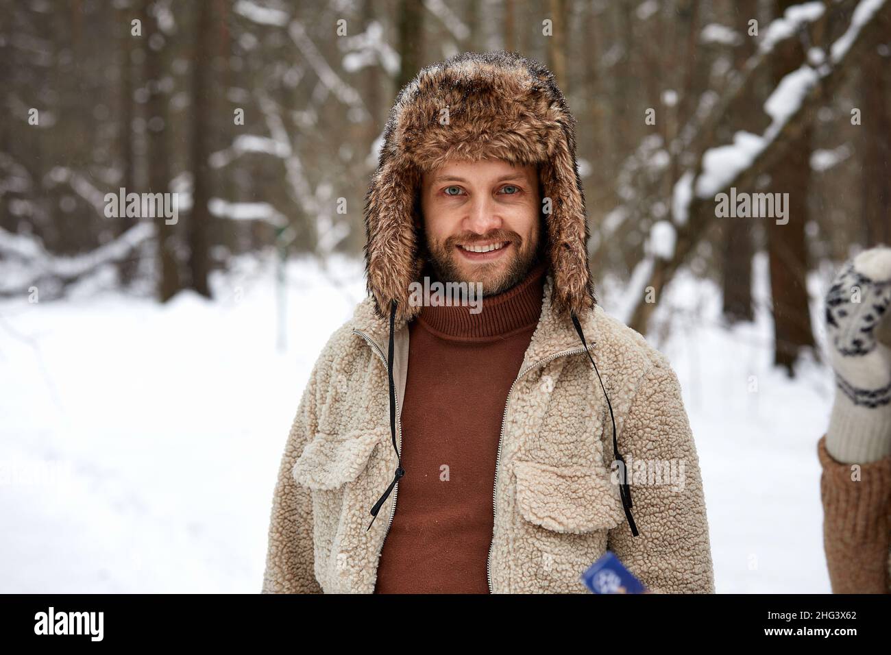 Smiling handsome man in worm hat is enjoying cold snowy weather in ...