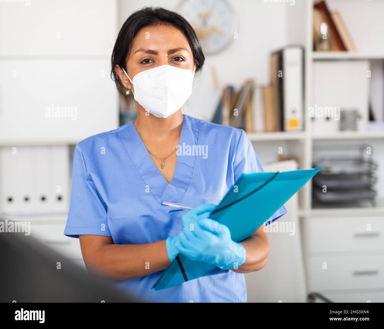 Female doctor in mask filling out medical form at clipboard Stock Photo ...