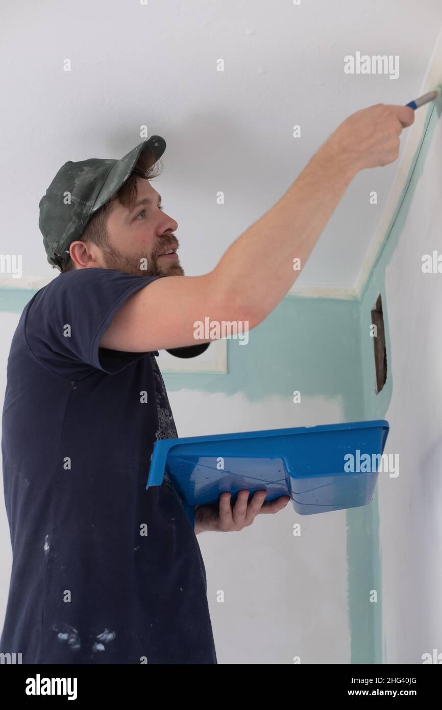 man painting a house wall with a paint Roller Stock Photo - Alamy