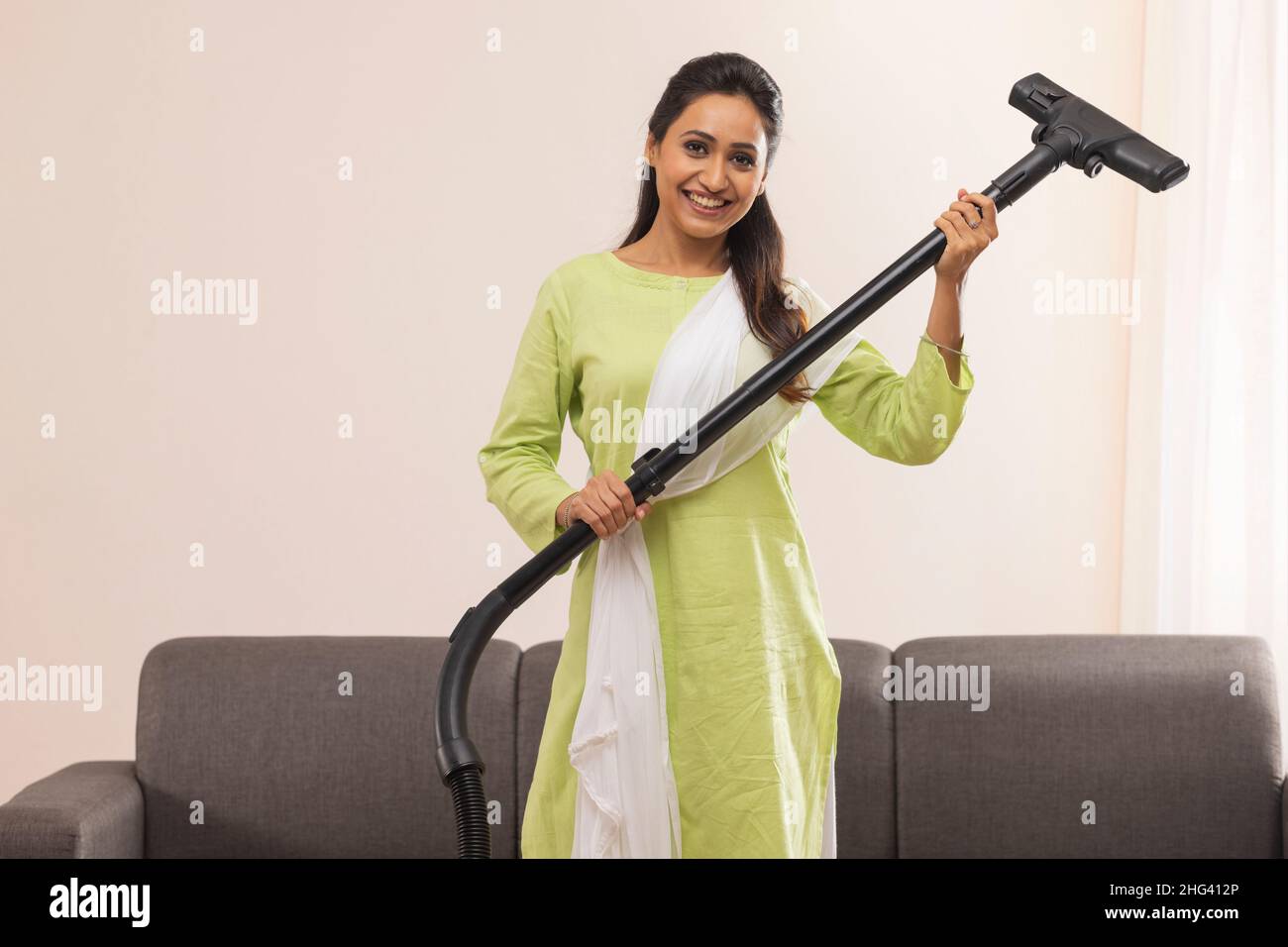 Woman posing with vacuum cleaner at home Stock Photo - Alamy