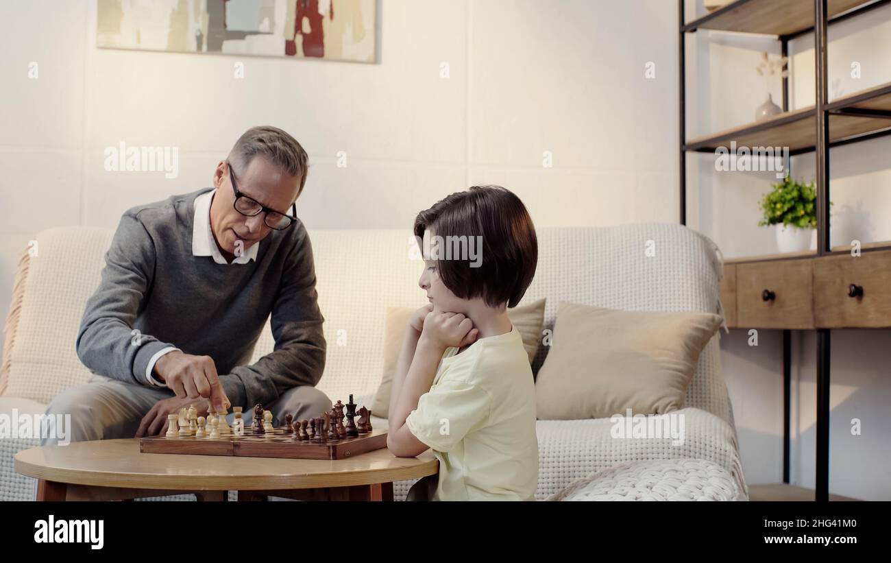 grandfather and grandson playing chess in living room Stock Photo - Alamy
