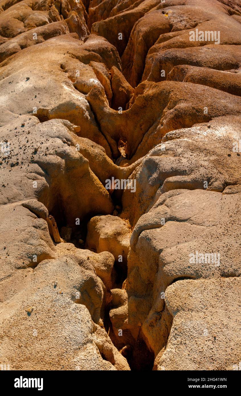 A close up of an erosion crack running through red dirt and earth in an ...