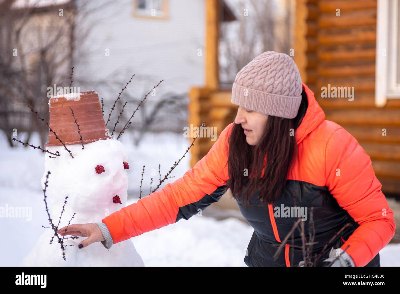 Middle aged woman by herself making snowman on backyard of cottage in ...