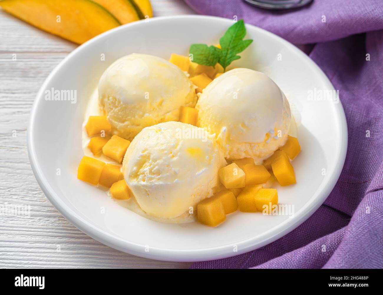 Three balls of mango ice cream in a plate on a light background. Side ...