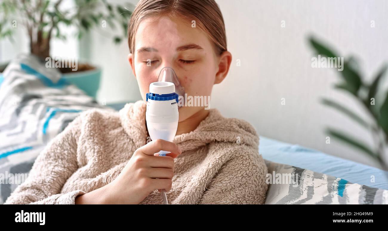 Teenage girl makes inhalation with a nebulizer equipment. Sick child ...