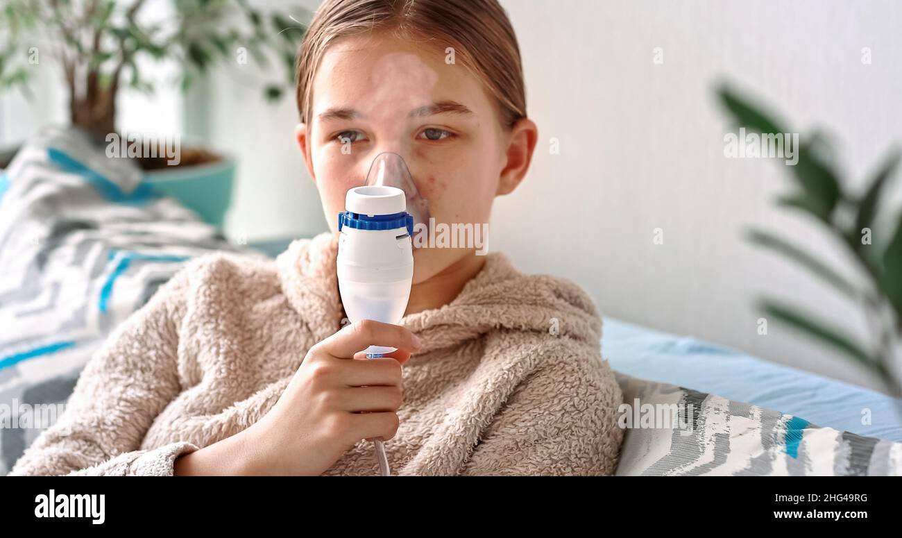 Teenage girl makes inhalation with a nebulizer equipment. Sick child ...