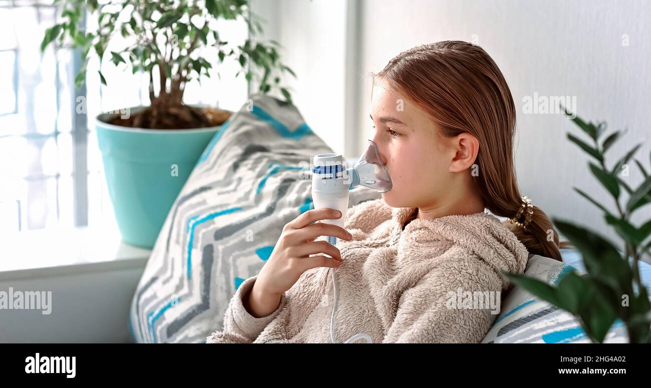 Teenage girl makes inhalation with a nebulizer equipment. Sick child ...