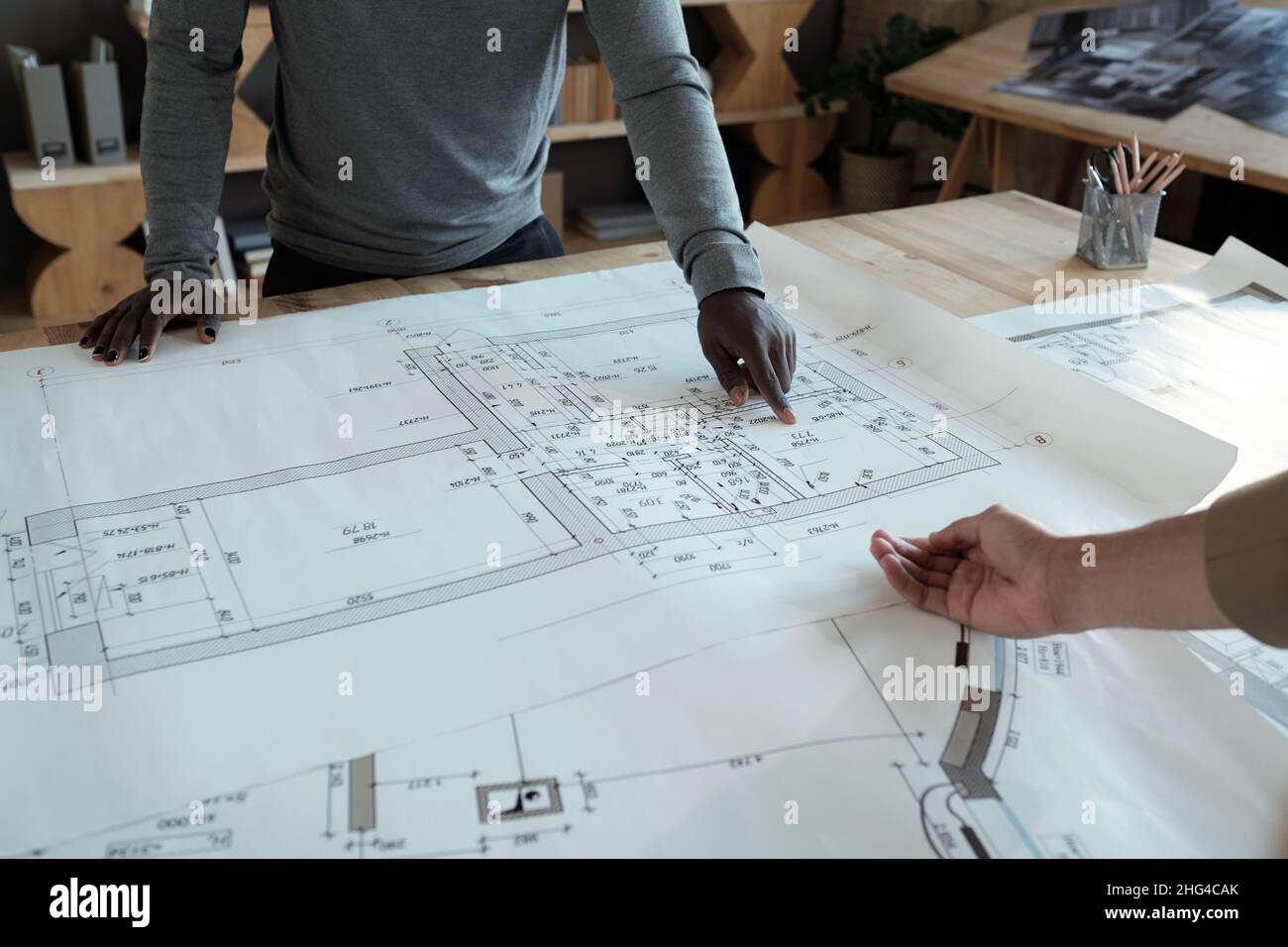 Hands of two young engineers discussing details of sketch on paper ...