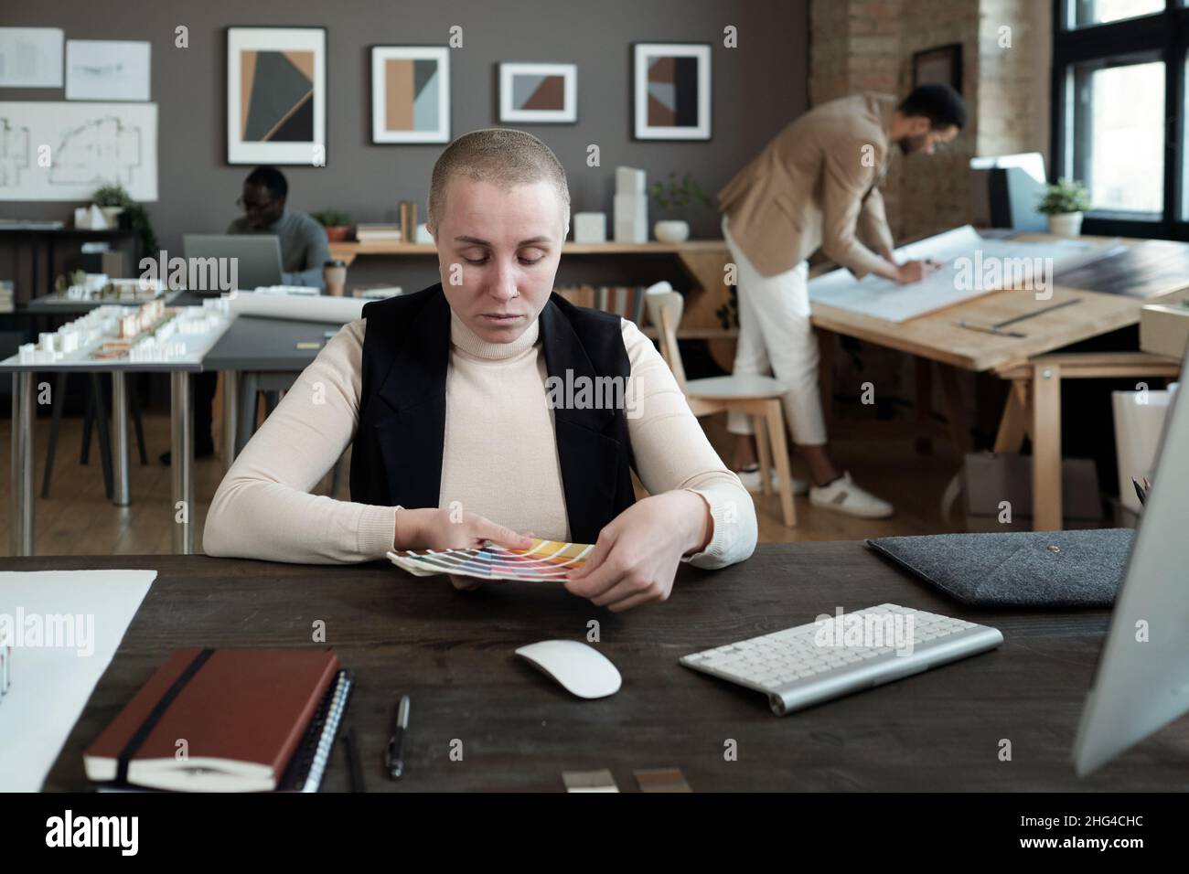Confident female designer looking at color palette in her hands while ...