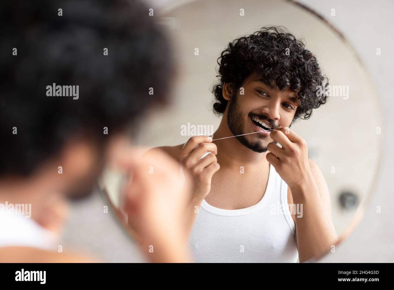 Toothcare concept. Bearded indian man using teeth floss caring for oral ...