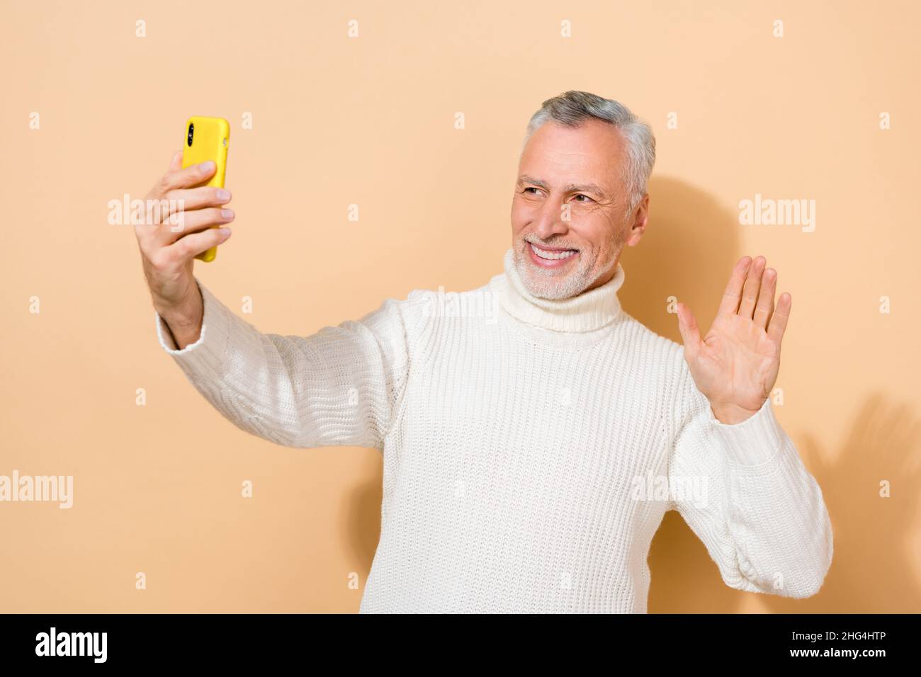 Portrait of attractive cheerful grey-haired man making taking selfie ...