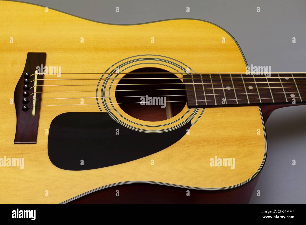 upper soundboard of an acoustic yellow guitar close-up on a gray ...