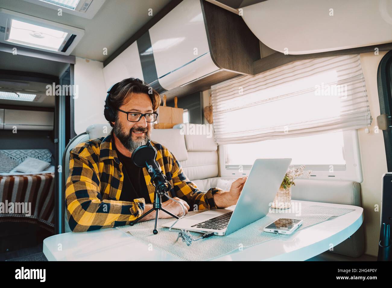 Young adult use microphone and laptop computer to podcast web content ...