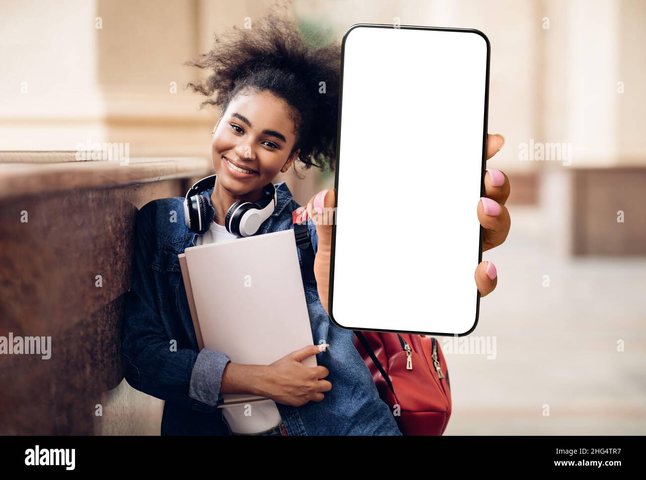 Happy african american female student demonstrating smartphone with big ...