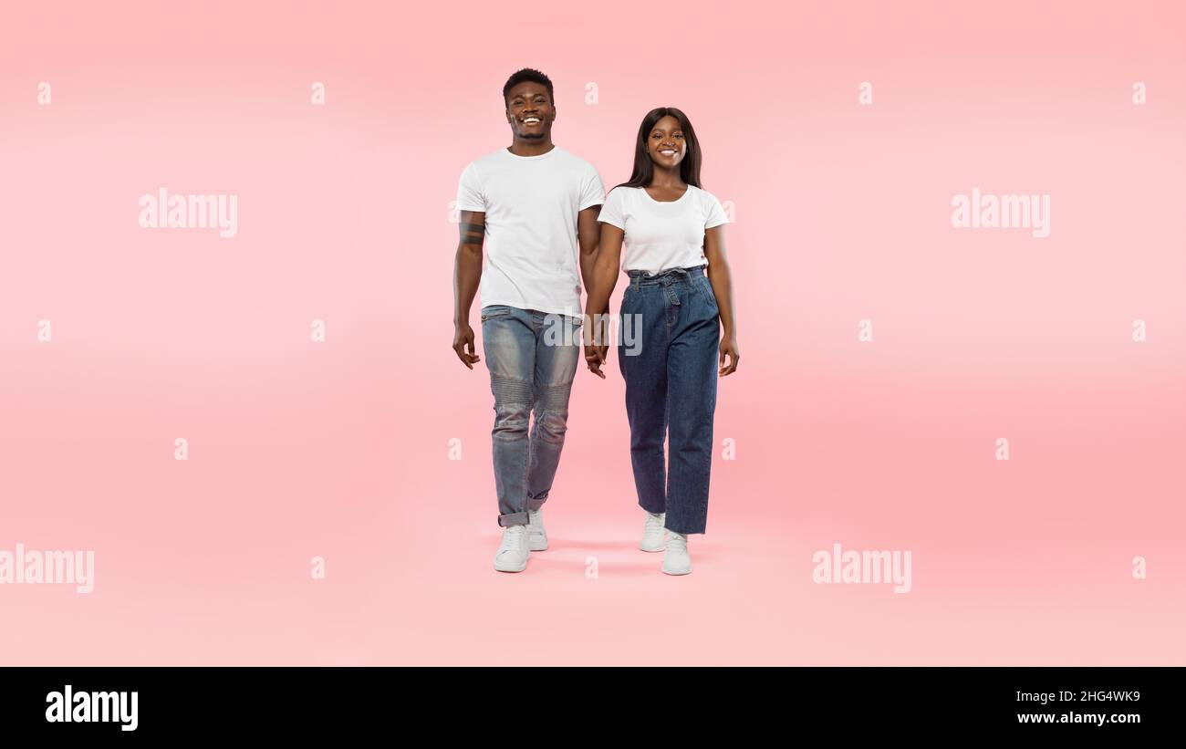 Confident couple walking to camera at pink studio background Stock ...