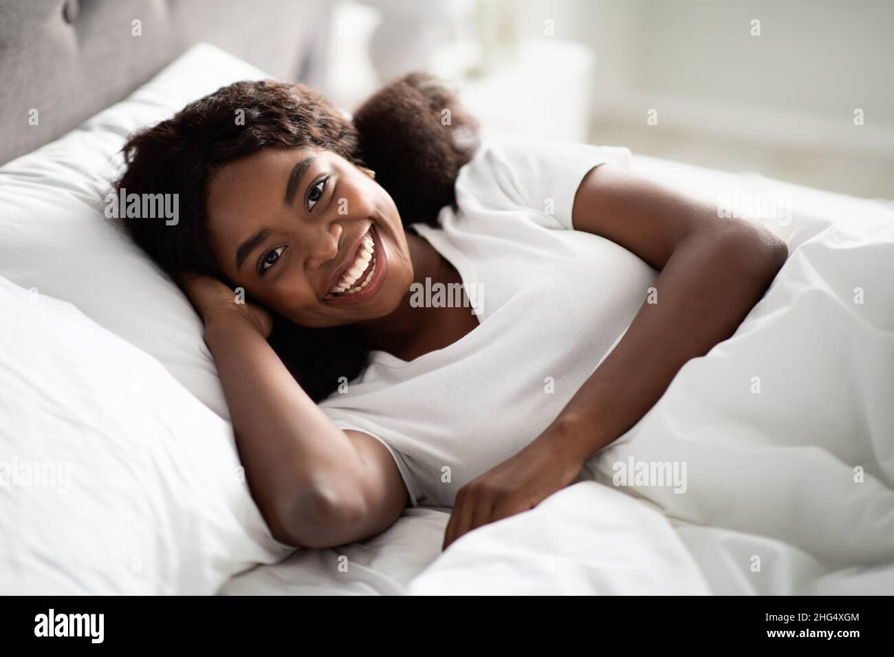 Closeup photo of happy pretty black lady laying in bed Stock Photo - Alamy