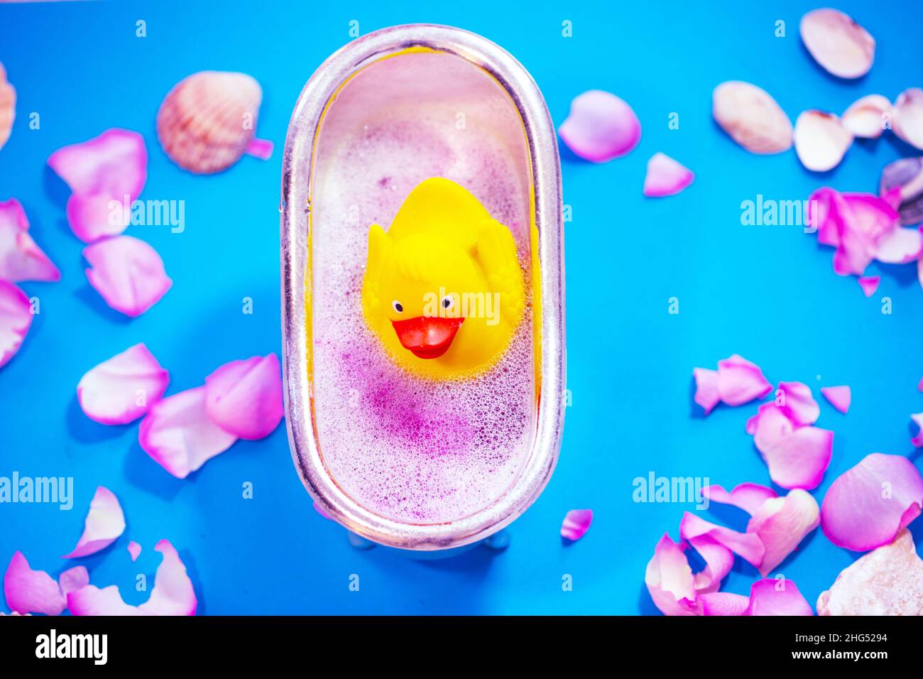 Rubber duck in the bathtub, colorful background with shells, rose ...
