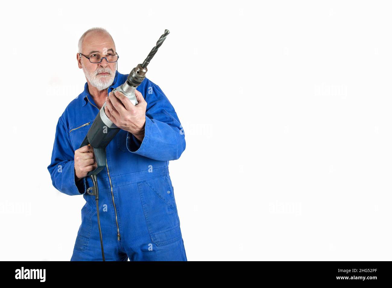 An older experienced craftsman holds his big drilling machine with a ...