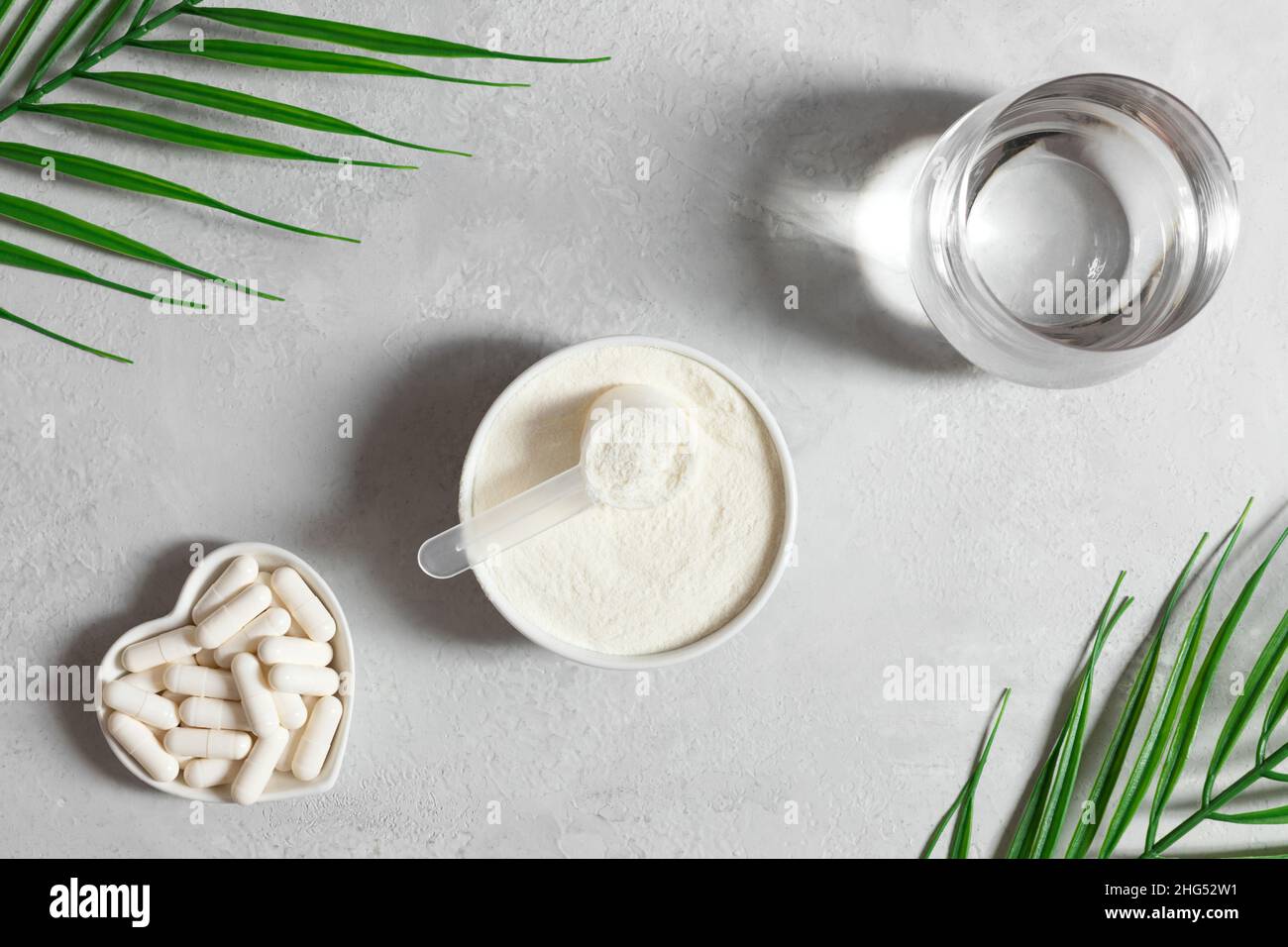 Collagen powder in a bowl, collagen capsules and a glass of water on a ...
