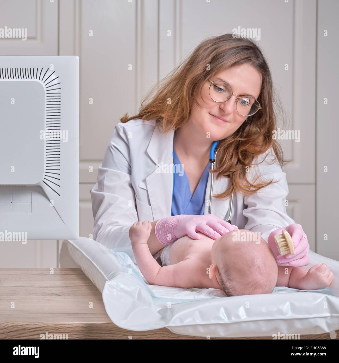 The doctor is combing the hair of a newborn baby. Nurse in uniform with ...