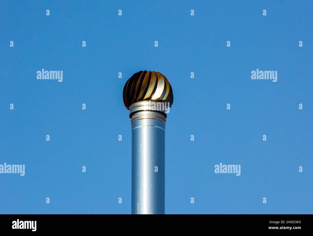 detail of steel chimney with rotating head on a background of blue sky ...