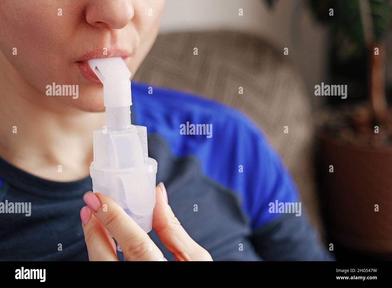 Inhalation at home. Woman inhales couple of drugs, holds nebulizer tube ...