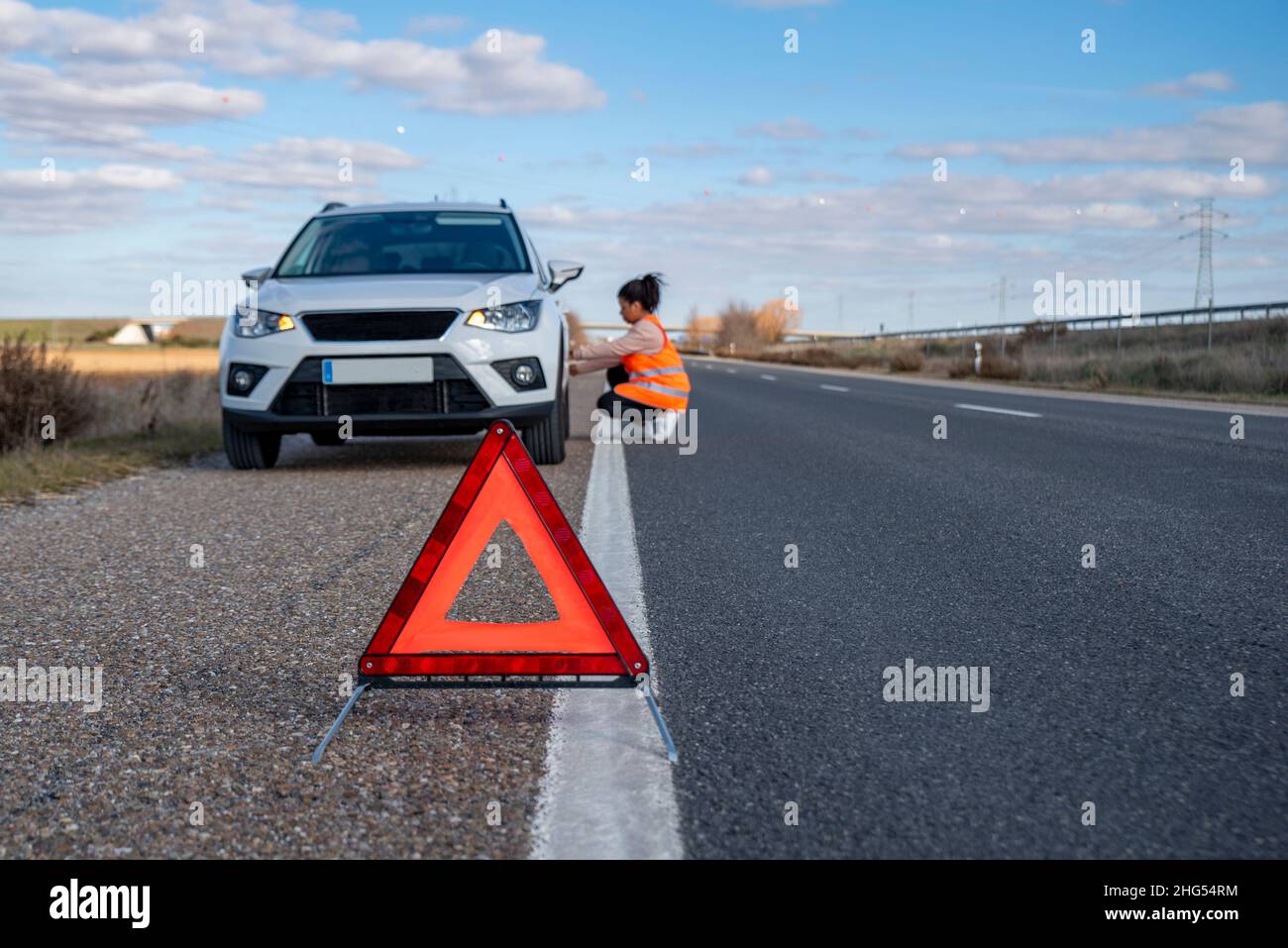 Young sad african woman stand with emergency triangle against car with ...