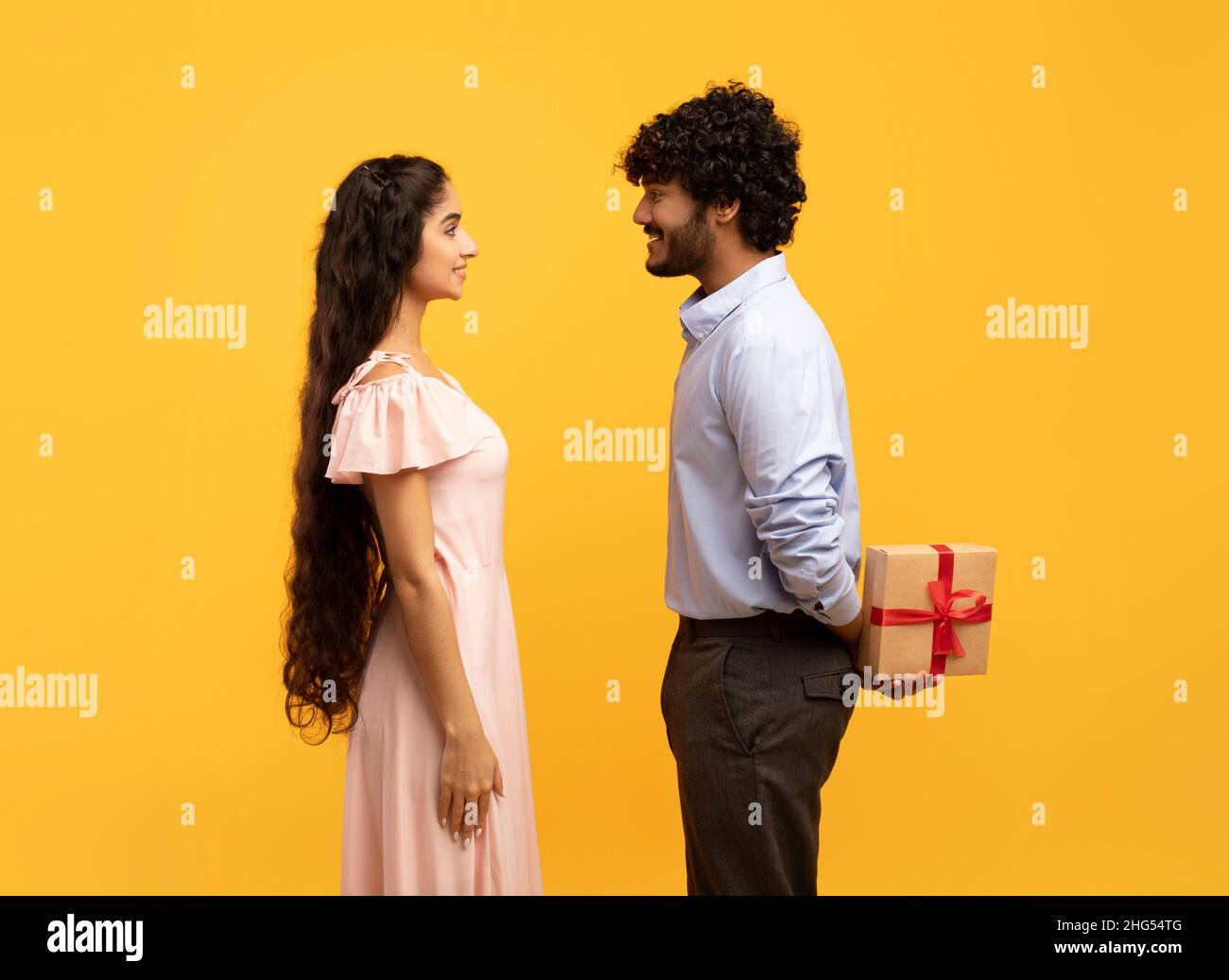 Excited indian guy holding wrapped gift box, hiding present for his ...