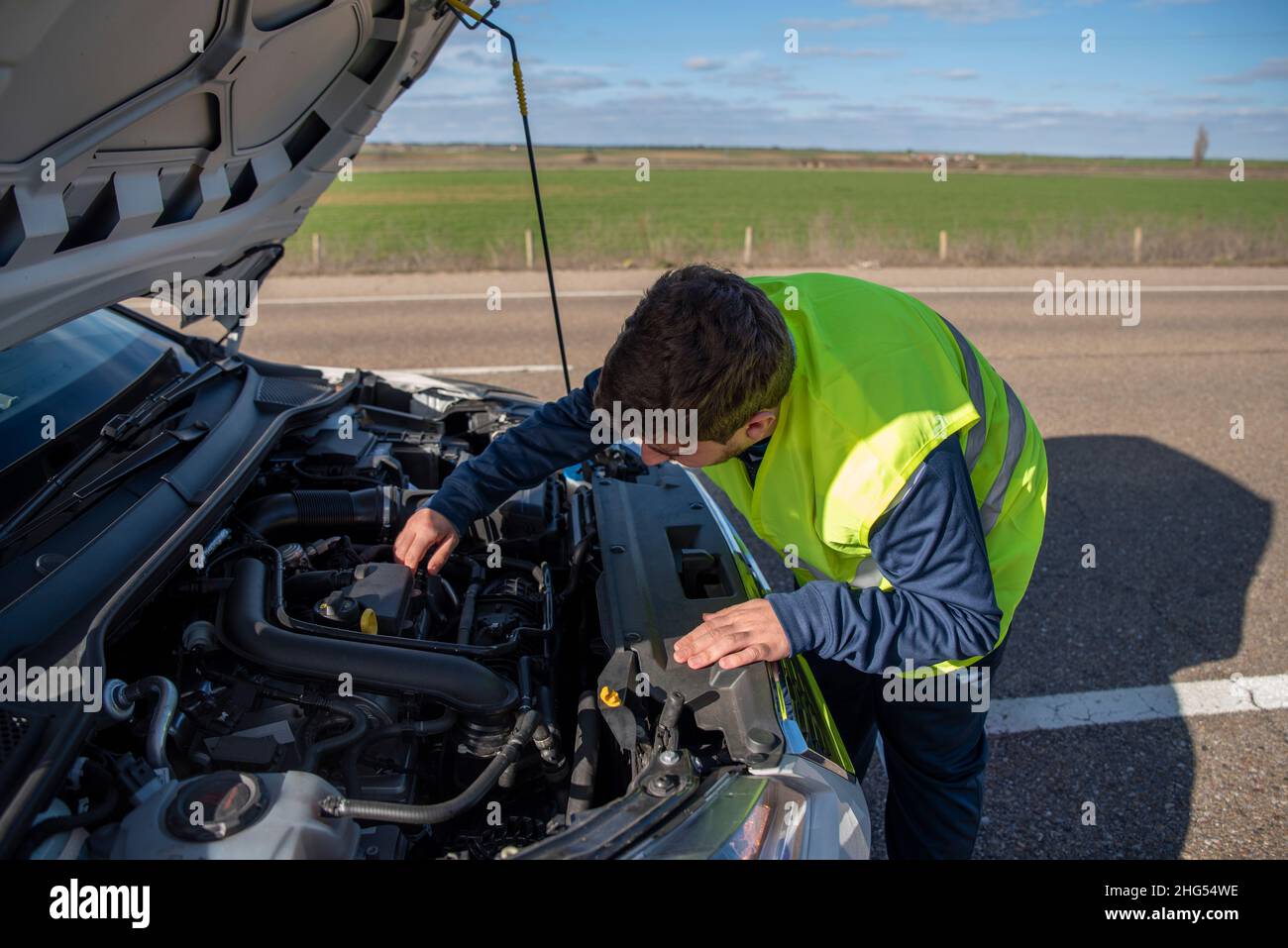 Close up of young man's hands examining broken car engine, standing ...