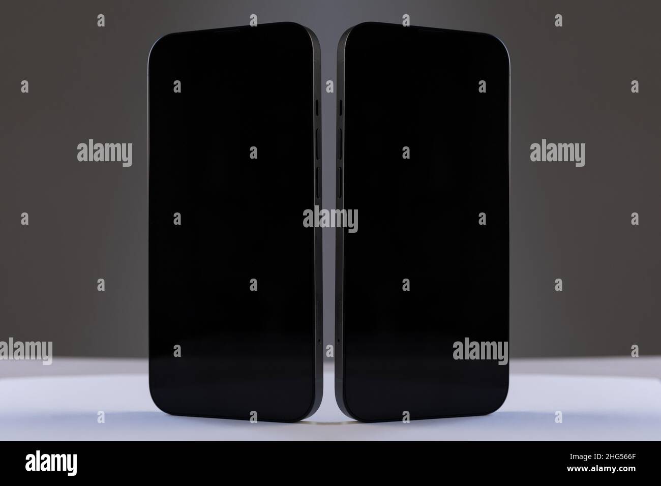 two black rectangular smartphones with glossy screens next to each ...