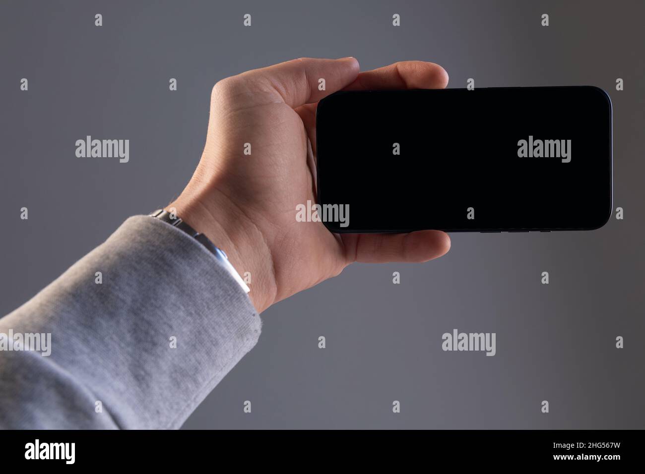 black rectangular modern smartphone in a male hand on a gray isolated ...