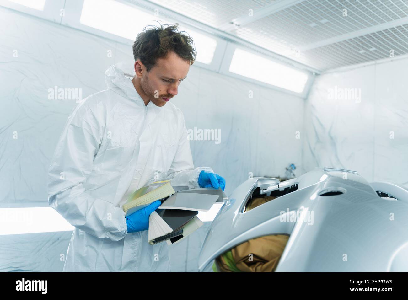 Car painter selects the shade of the automobile color using samples ...