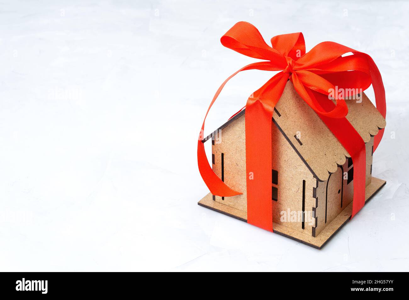 Miniature wooden house wrapped with a red ribbon with a bow on top ...