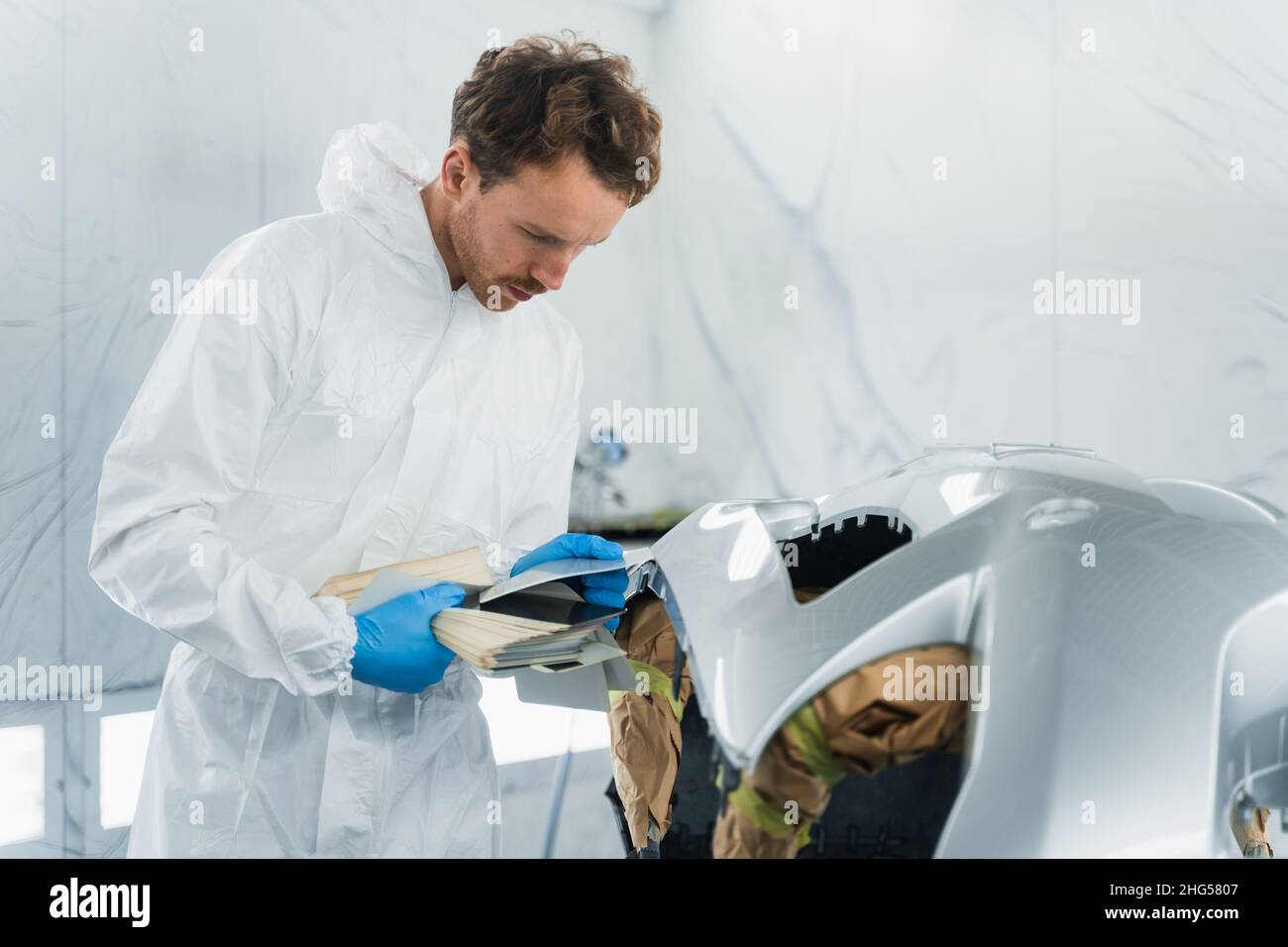 Auto paint specialist choosing color for car bumper. Man compares the ...