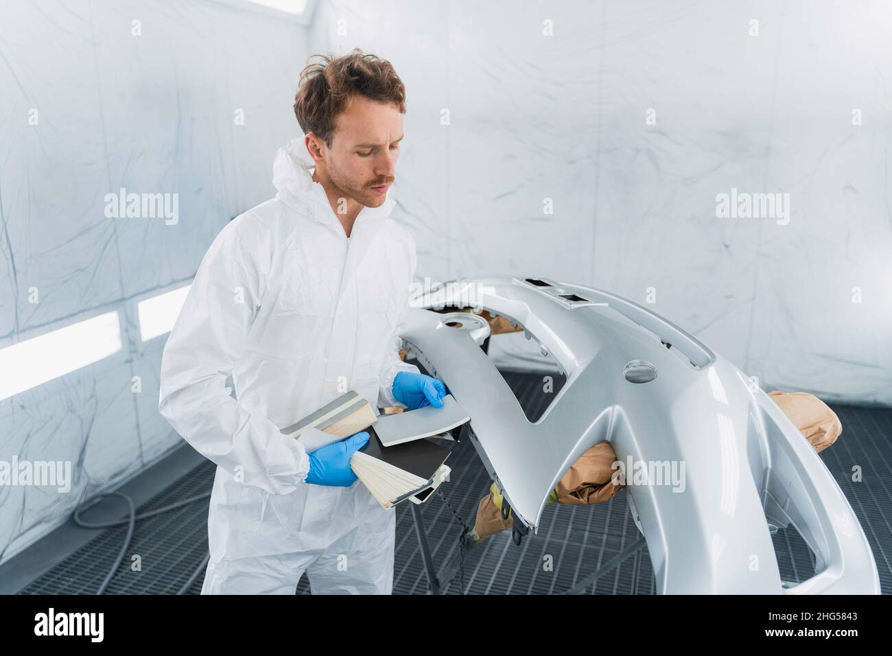 Auto painter works with samples of car paint colors in the automobile ...