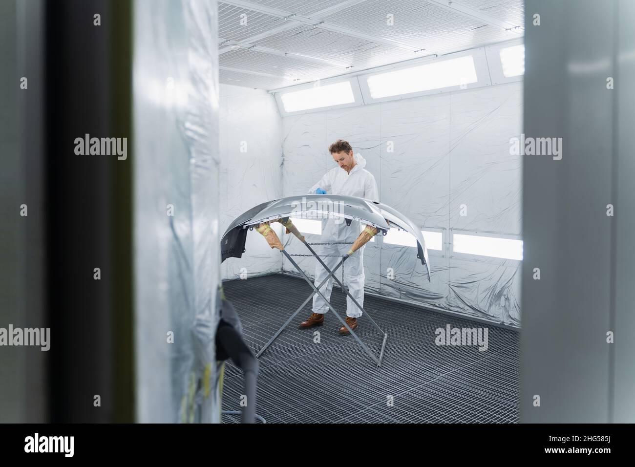 Auto painter working with bumper in car painting booth Stock Photo - Alamy