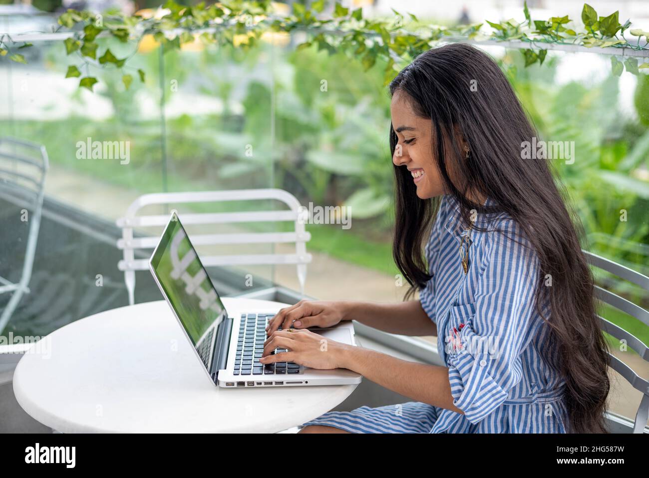 Young female entrepreneur using laptop while sitting on terrace of cafe ...
