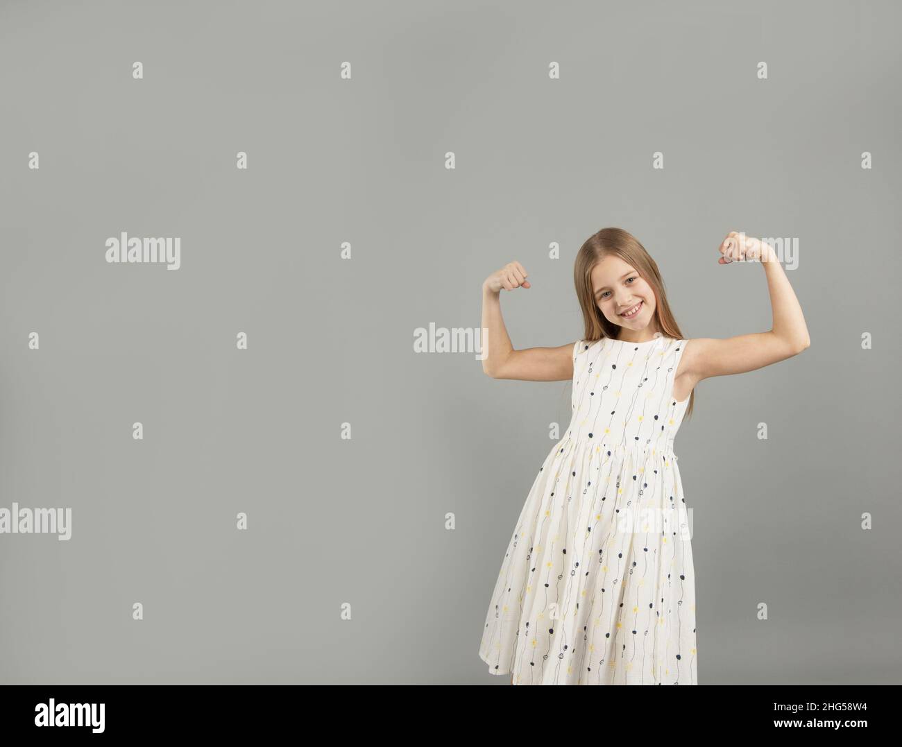 A beautiful girl demonstrating the strength of her hands on a gray ...