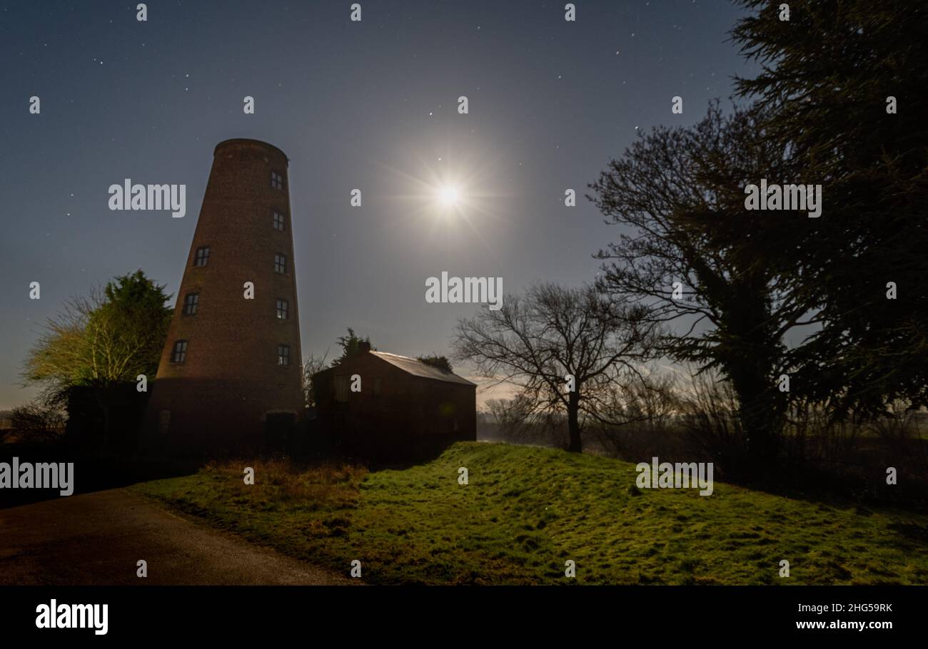 Wolf Moon shining on a derelict windmill, with woodland and starry sky ...