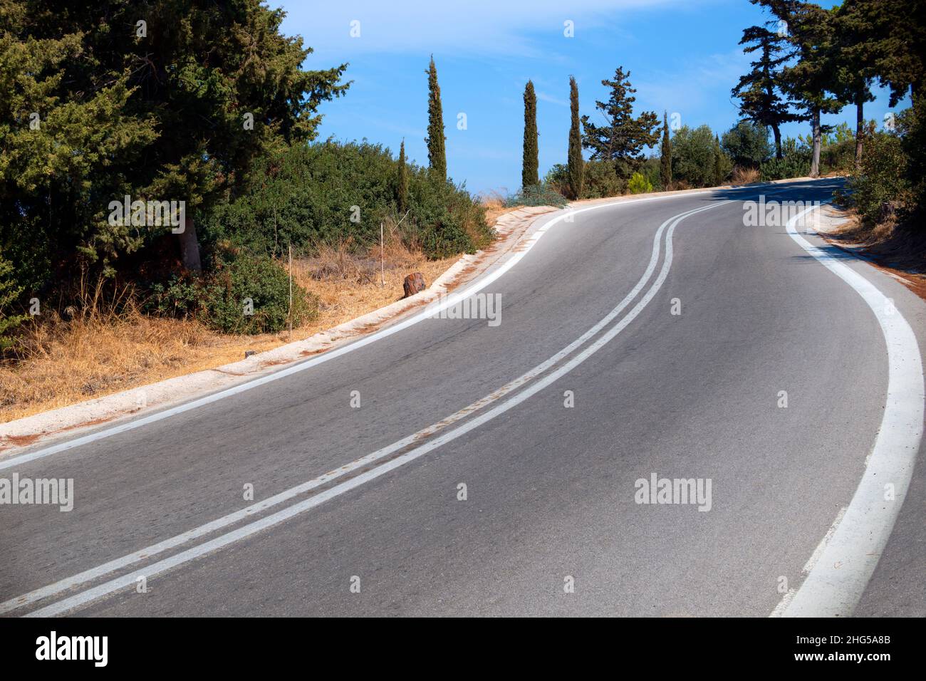 Switchback asphalt road between trees during sunny day in summer Stock ...