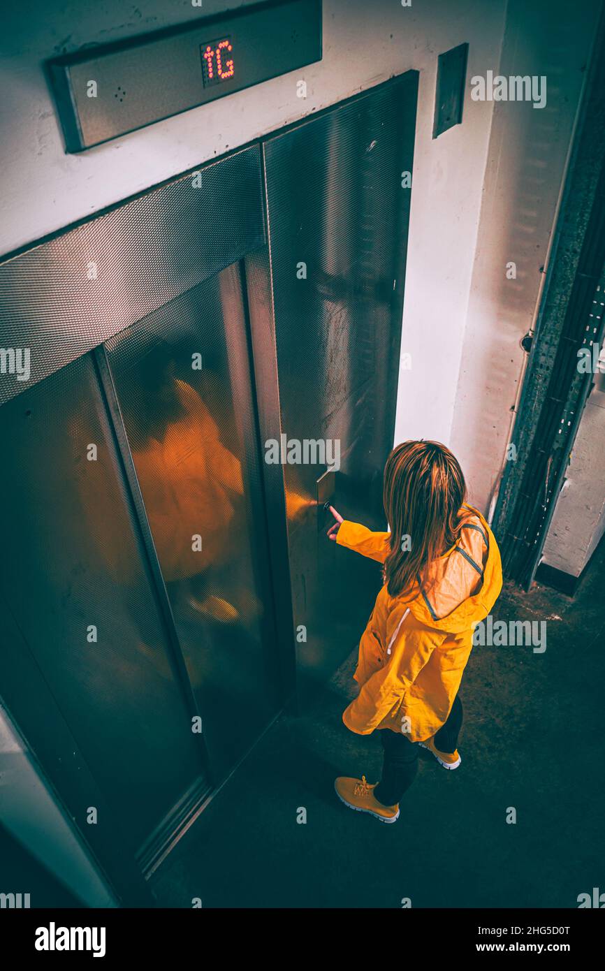 Woman wearing a yellow coat waiting for the lift in a car park Stock ...