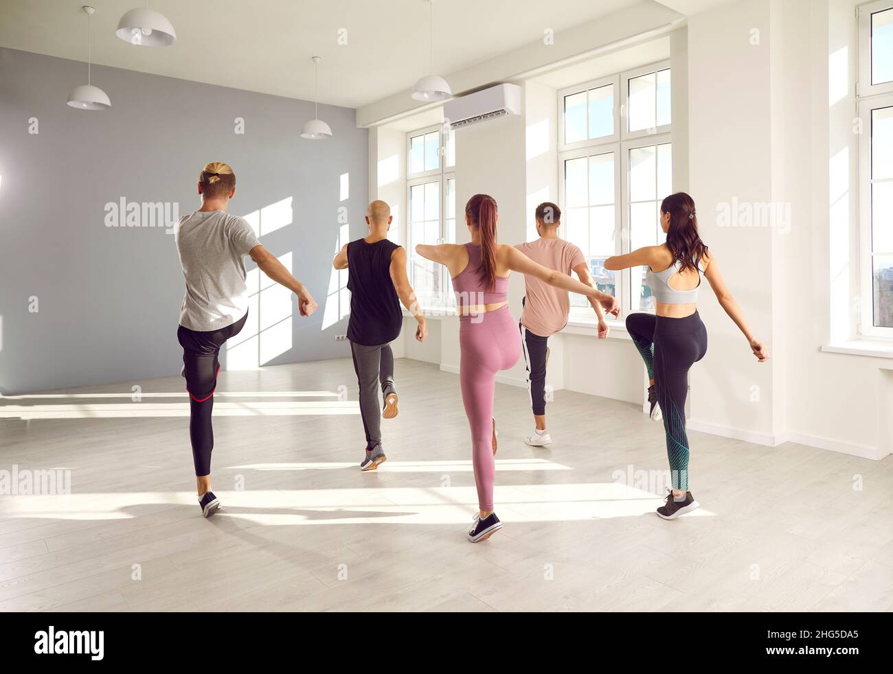 Group of energetic young people having a fitness workout class with a ...