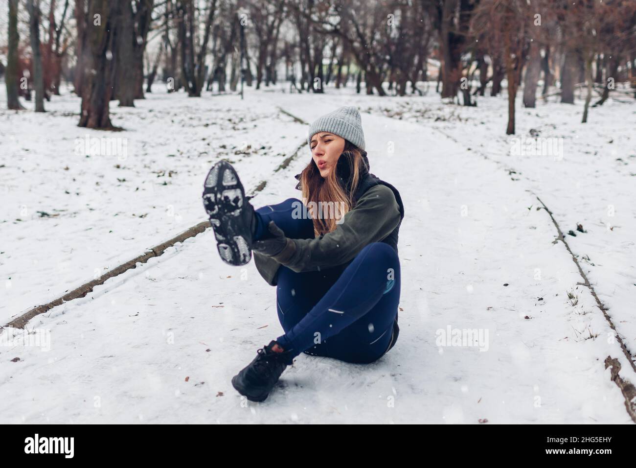 Runner woman fell down during training in snowy winter park. Woman ...