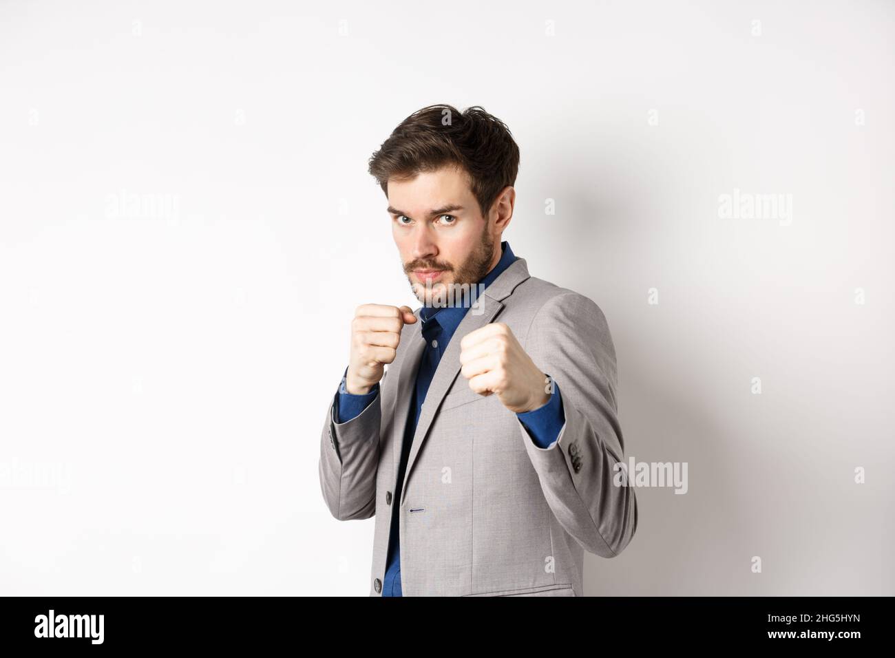 Serious man in suit raising hands in boxer pose, going to fight ...
