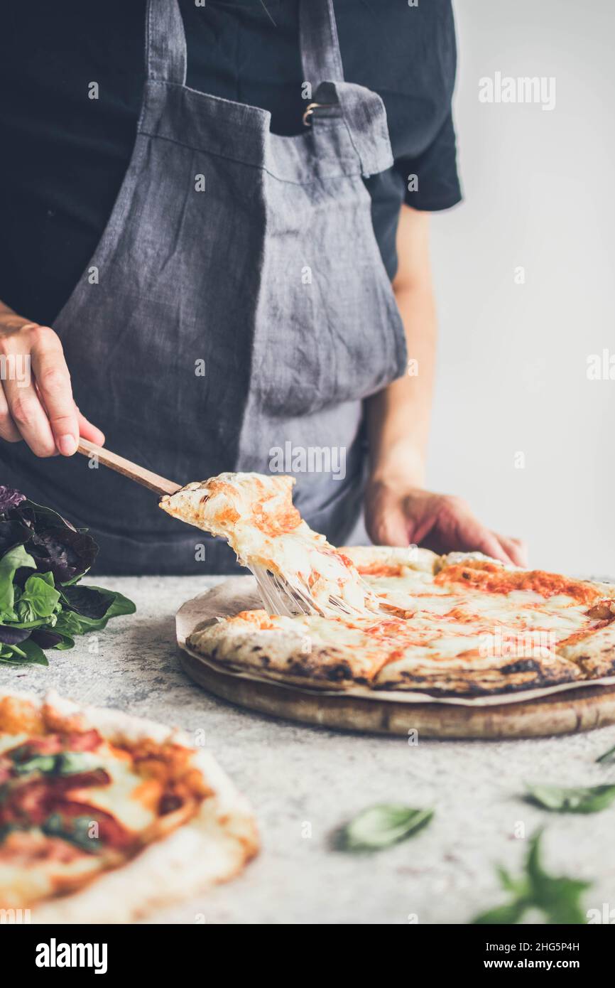 Woman serving hot pizza and slice with melting cheese pull Stock Photo ...
