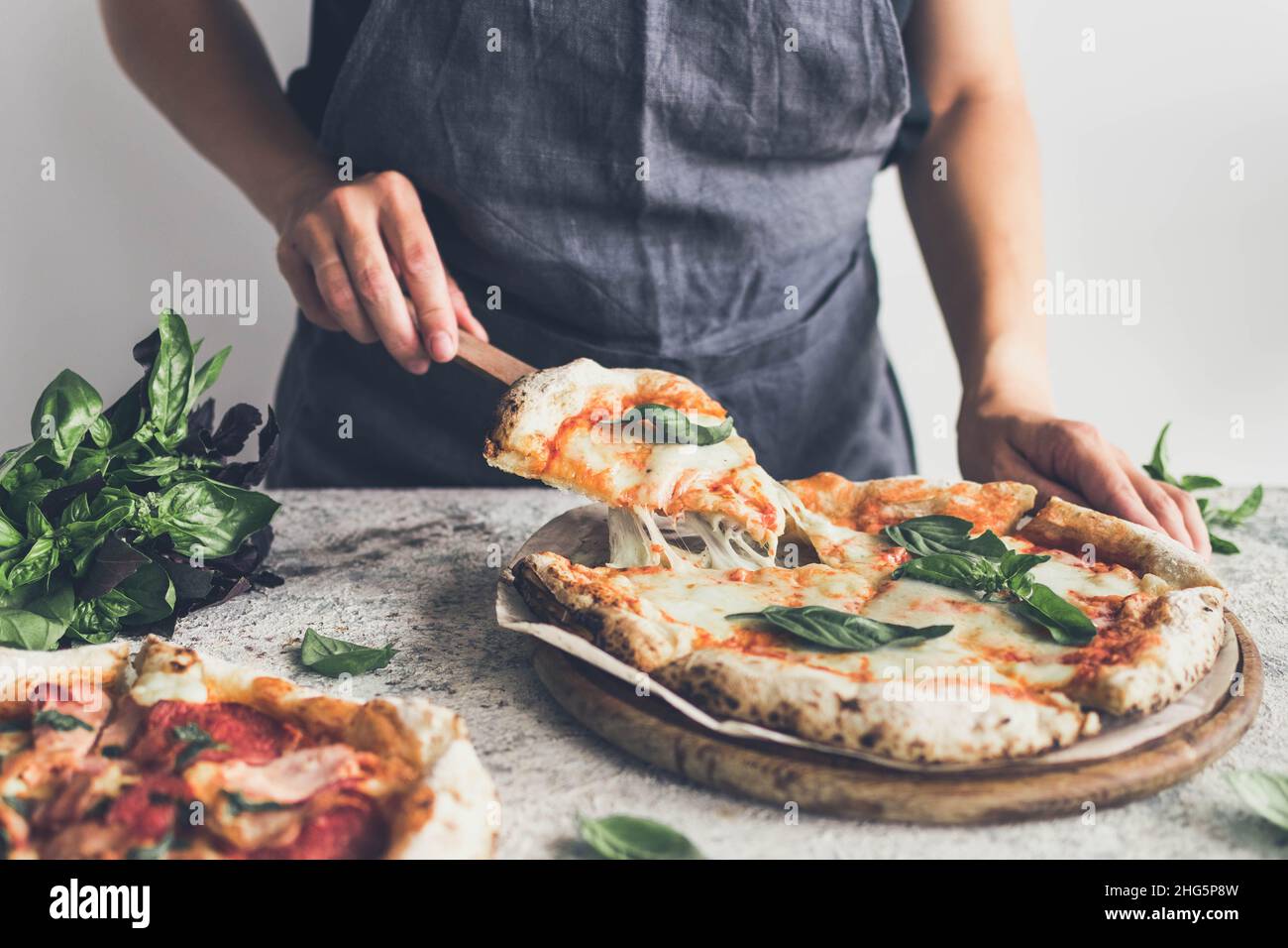 Woman serving hot pizza and slice with melting cheese pull Stock Photo ...