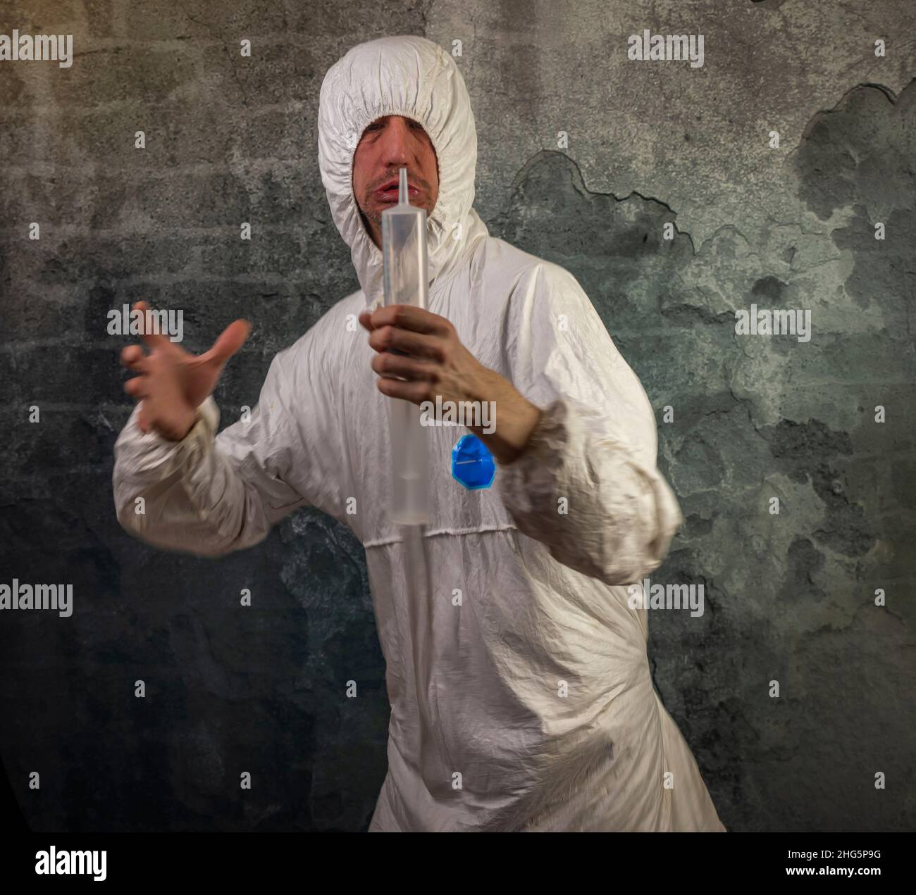 Man with white protection suit and big shot injection near old brick ...